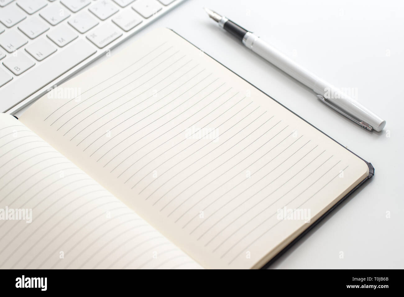 white table with notepad, keyboard and fountain pen. View from above ...