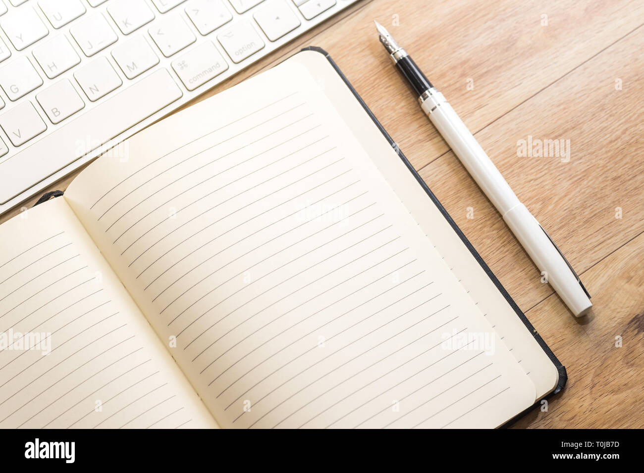 Office table with notepad, keyboard and fountain pen. View from above ...