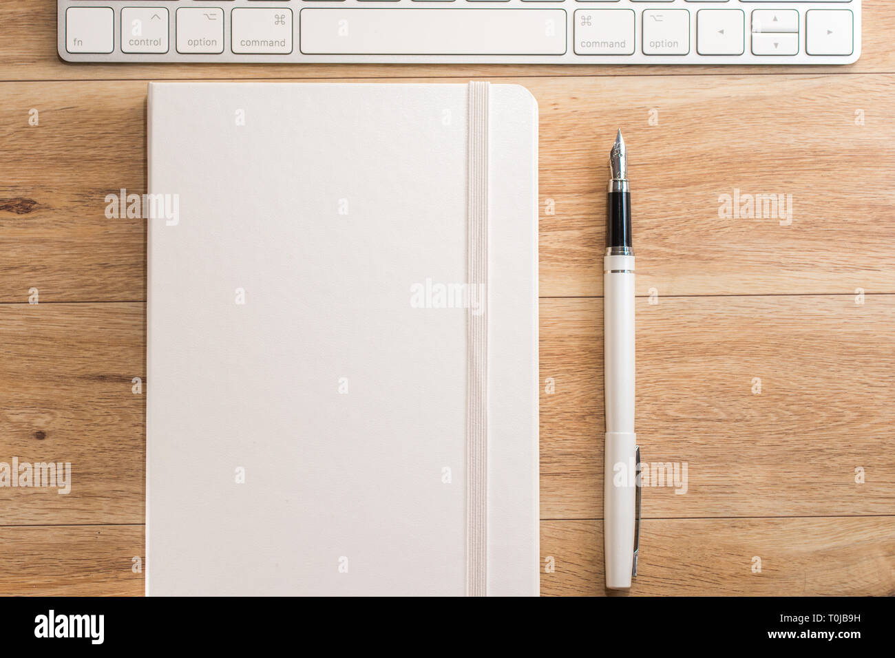 Office table with notepad, keyboard and fountain pen. View from above ...
