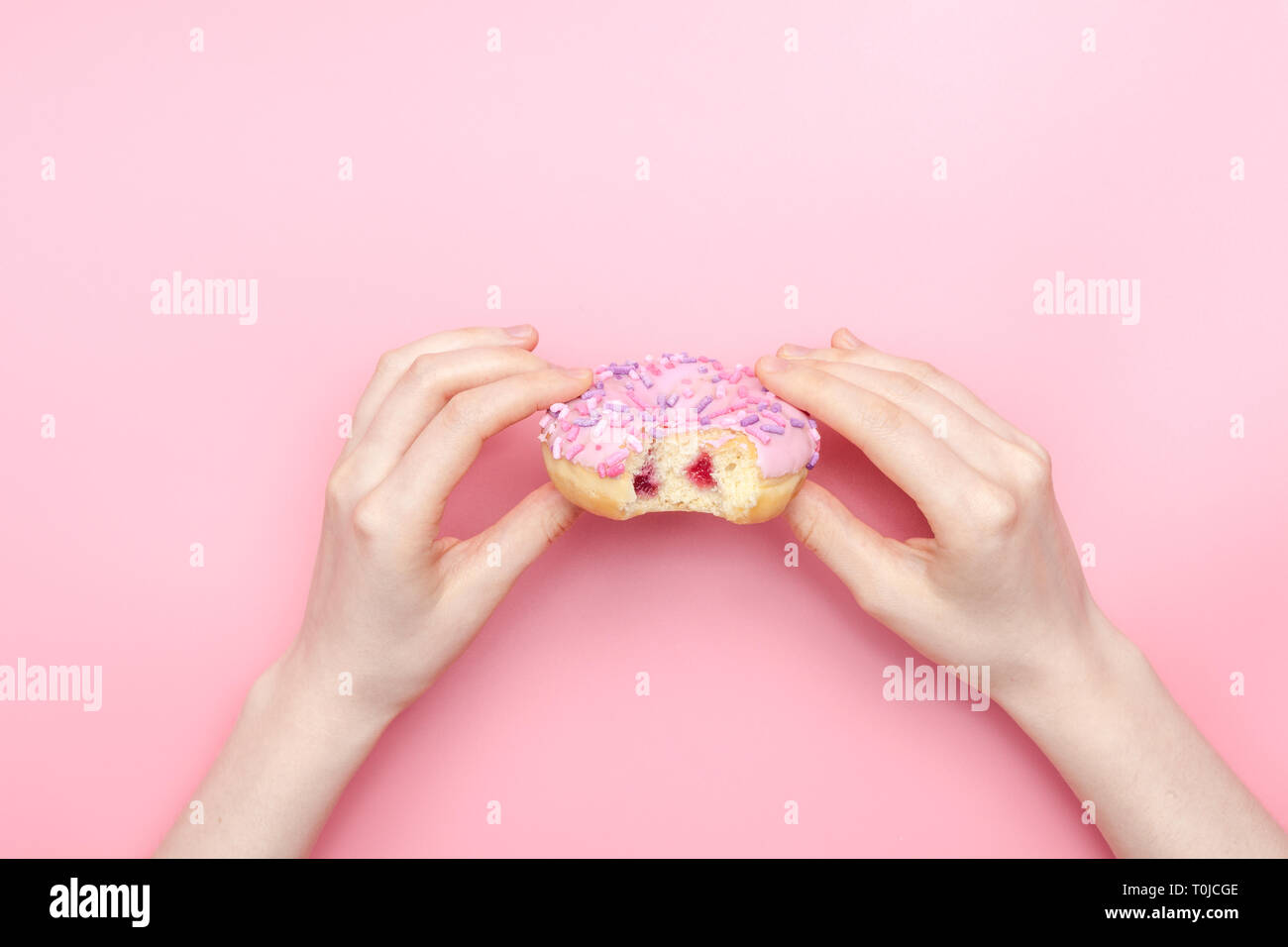 girl holding a glazed pink donut on a pink monochromatic background ...