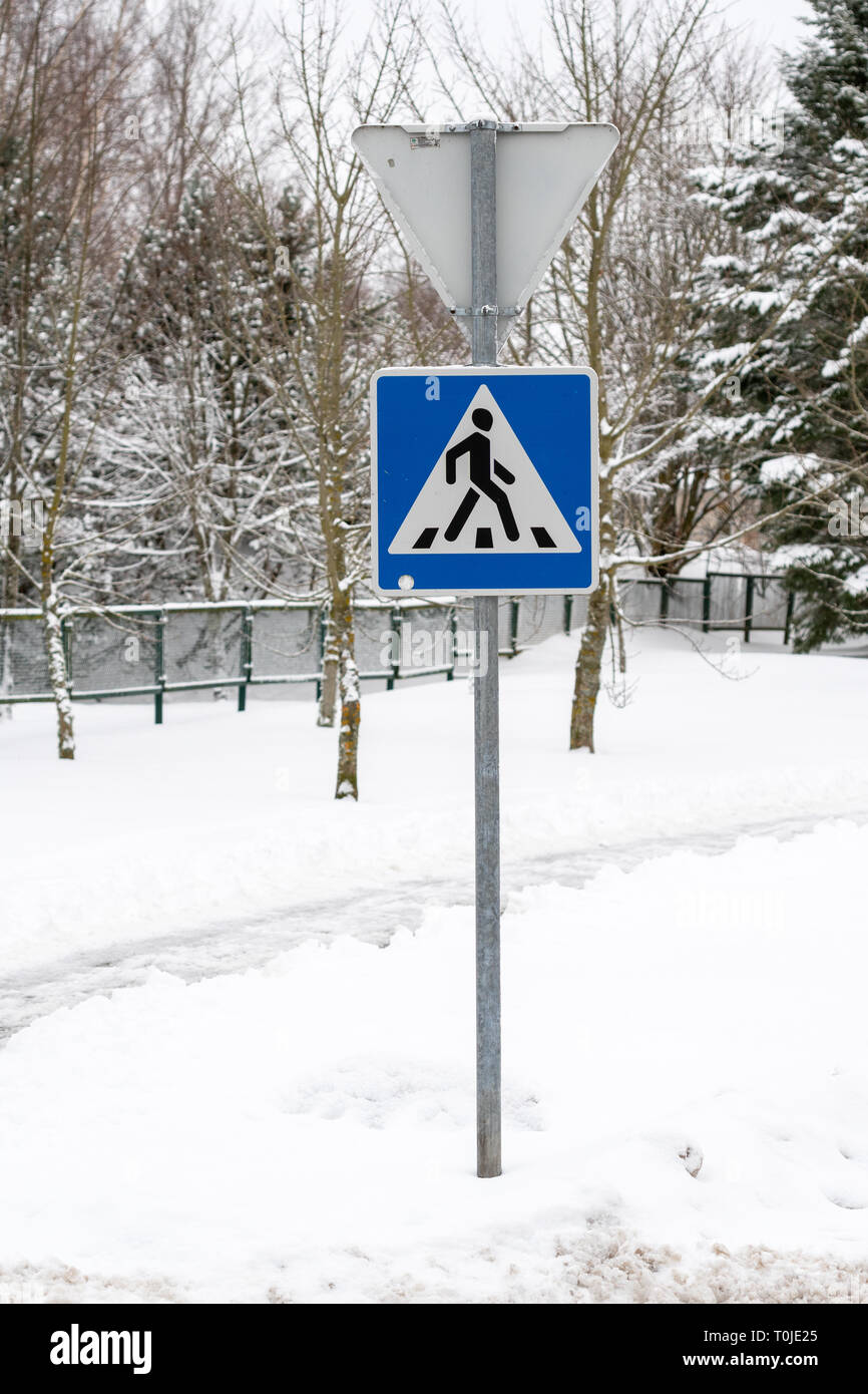 Pedestrian crossing road sign with snow. Safe driving in winter time ...