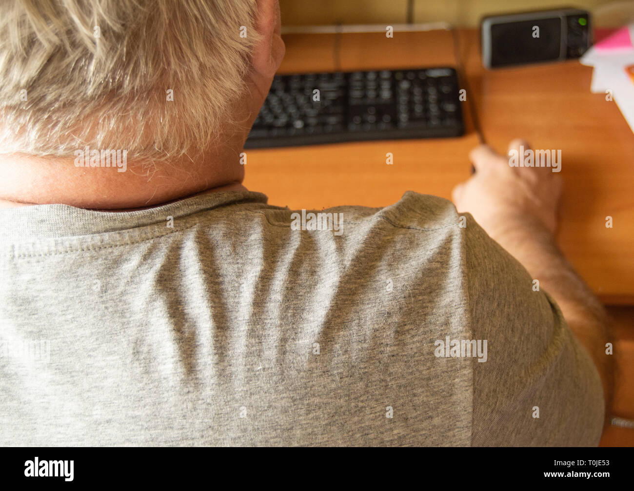 An elderly gray-haired man uses a computer mouse, work at home for the ...