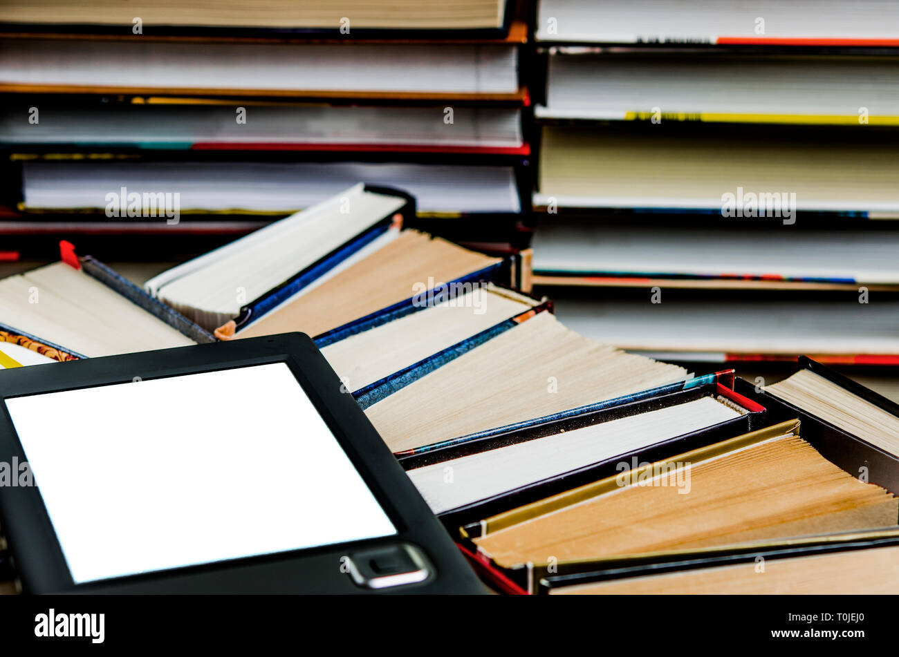 The e-book with a white screen lies on the open multi-colored books ...