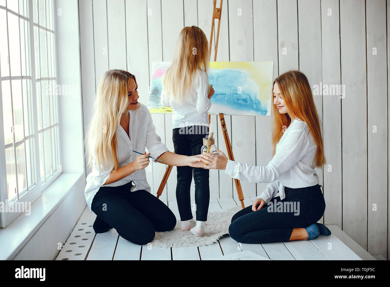 Beautiful little girl painting. Mother drawing with two girl. Family in ...