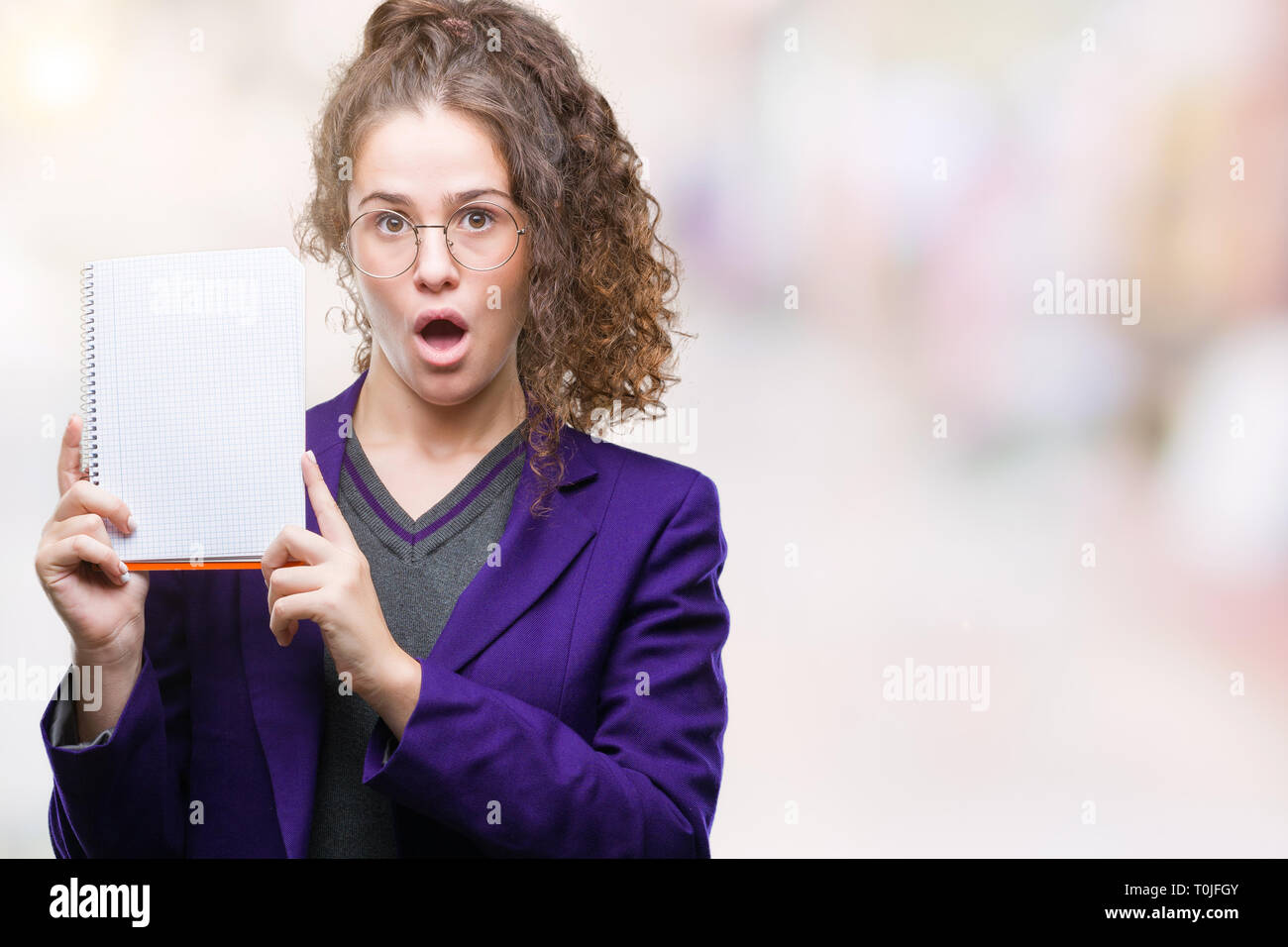 Young brunette student girl wearing school uniform holding a notebook ...