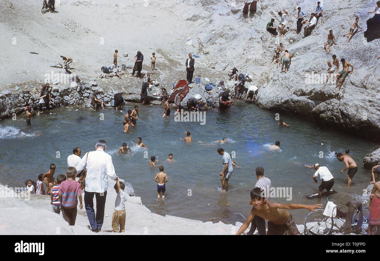 Families bathe and people wash oriental rugs at a desert oasis in Iran ...