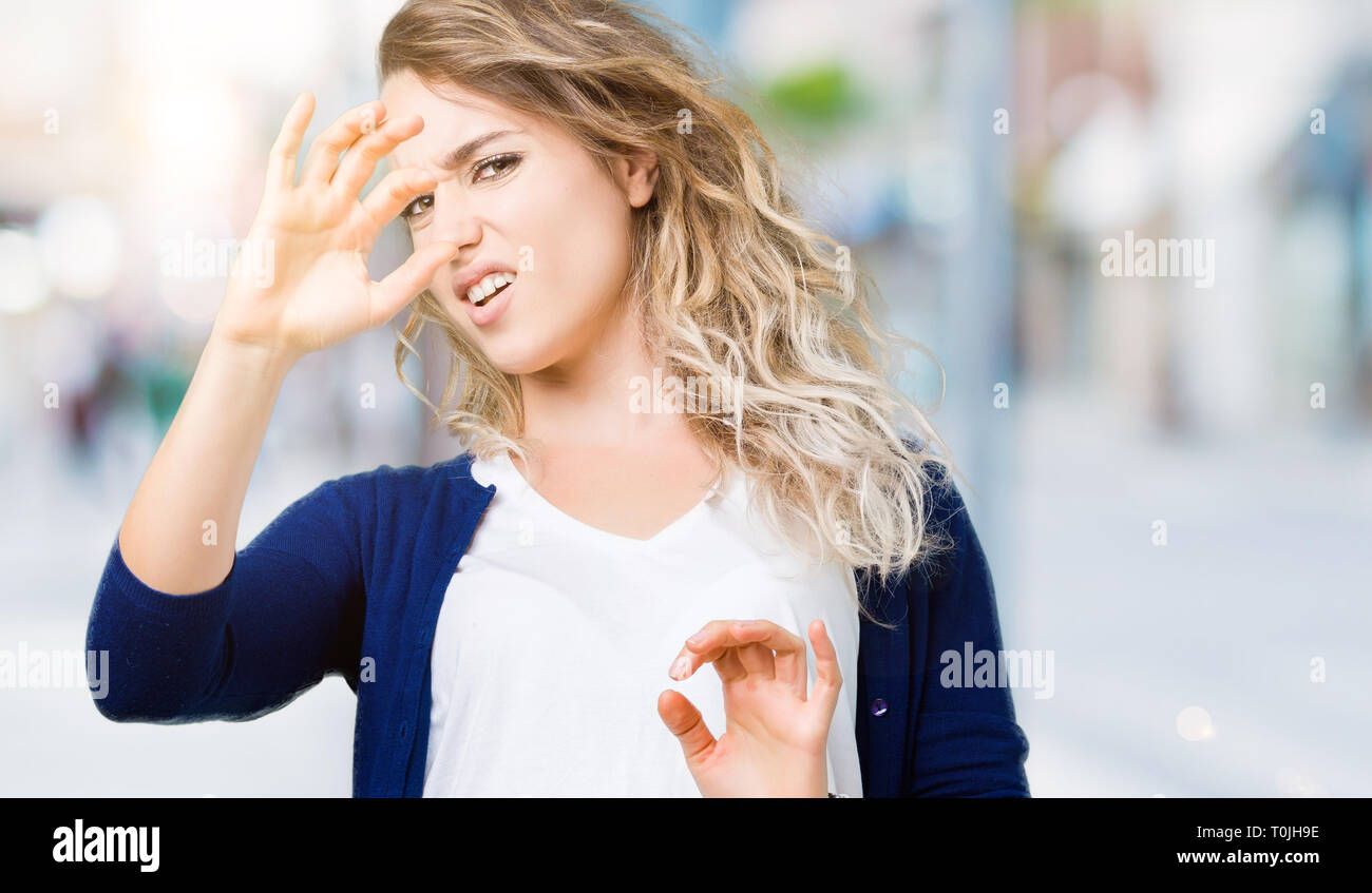 Beautiful young blonde woman over isolated background disgusted ...