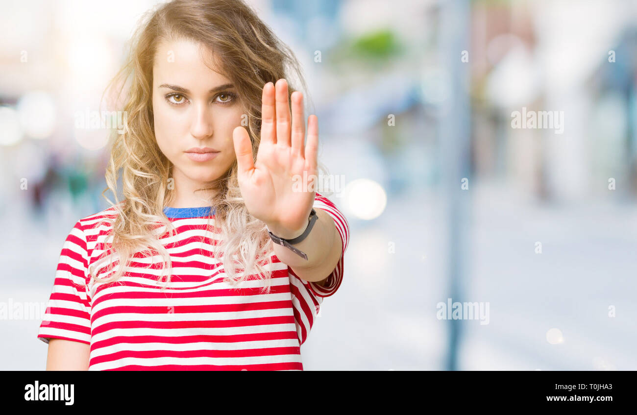 Beautiful young blonde woman over isolated background doing stop sing ...