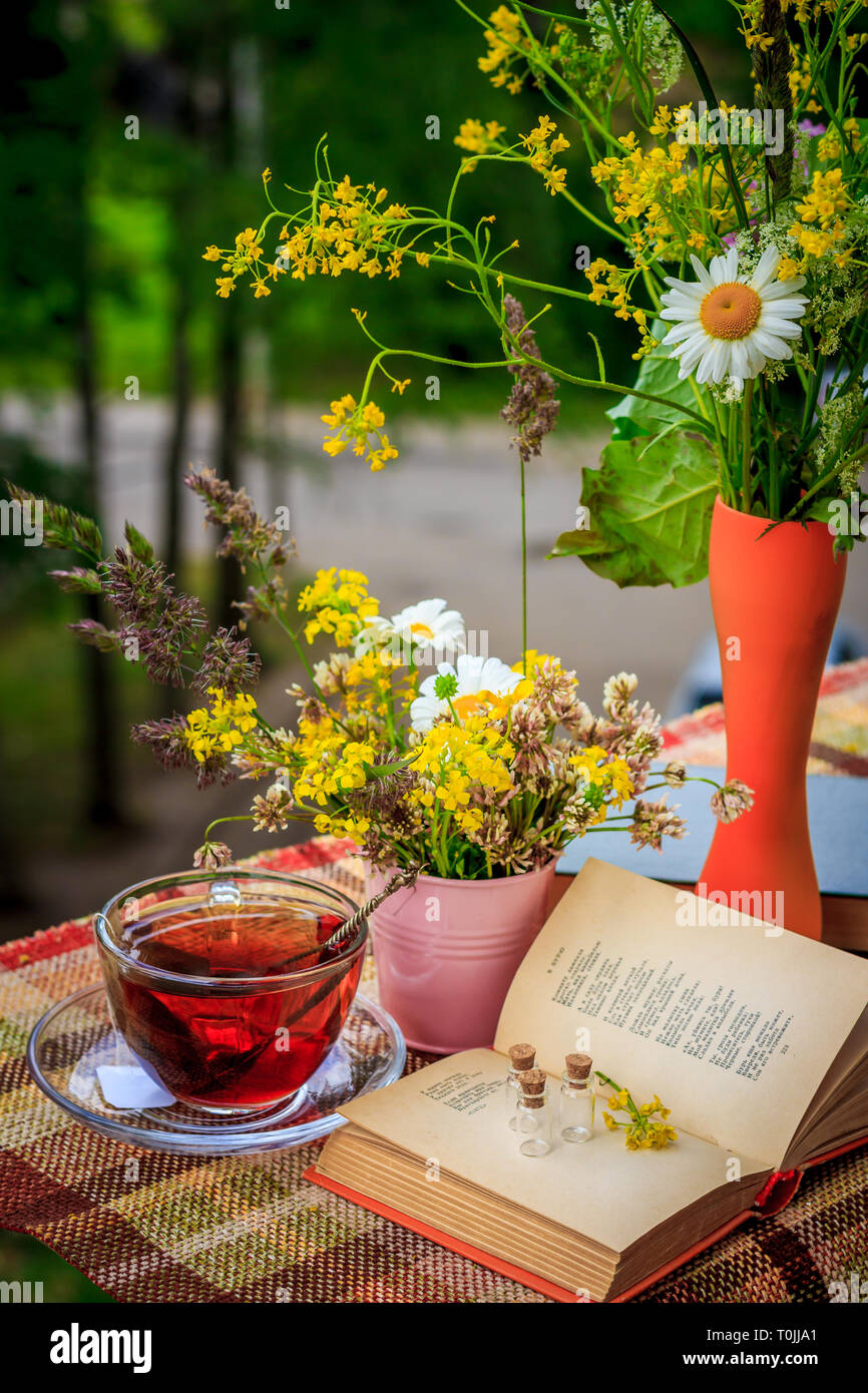 Summer tea with a book on the terrace. Summer tea with a bouquet of ...