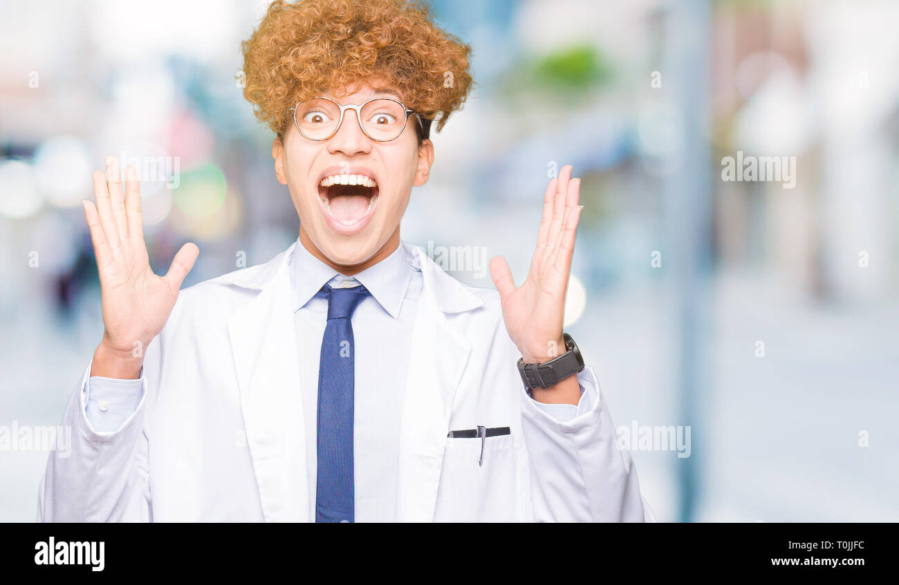 Young handsome scientist man wearing glasses celebrating crazy and ...