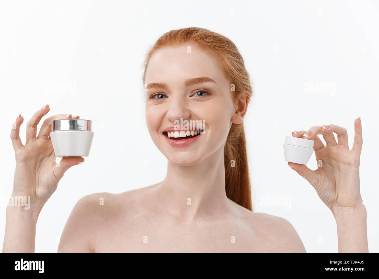 portrait of beautiful woman smiling while taking some facial cream ...