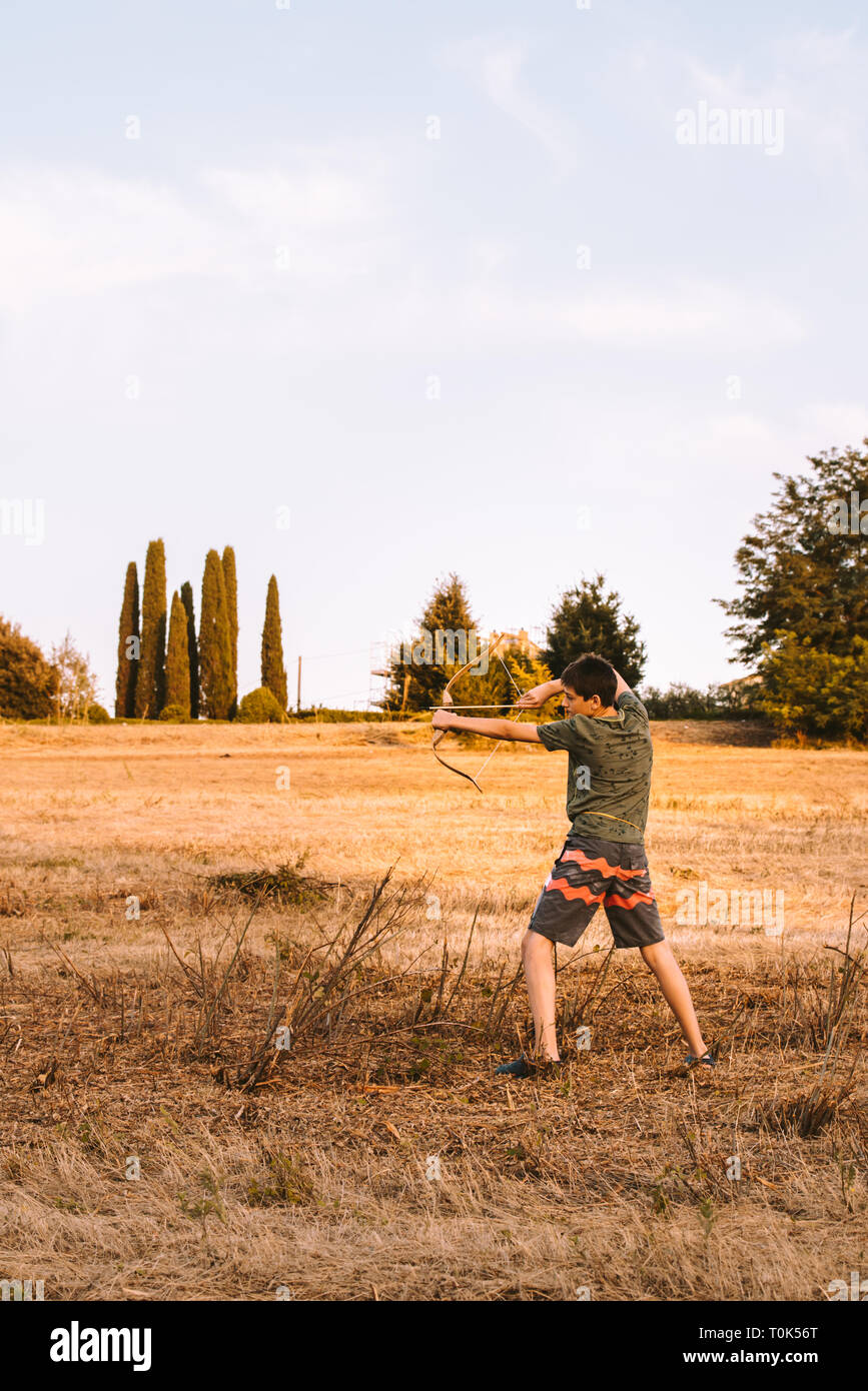 Young boy playing with bow and arrow in the beautiful fields, dry ...