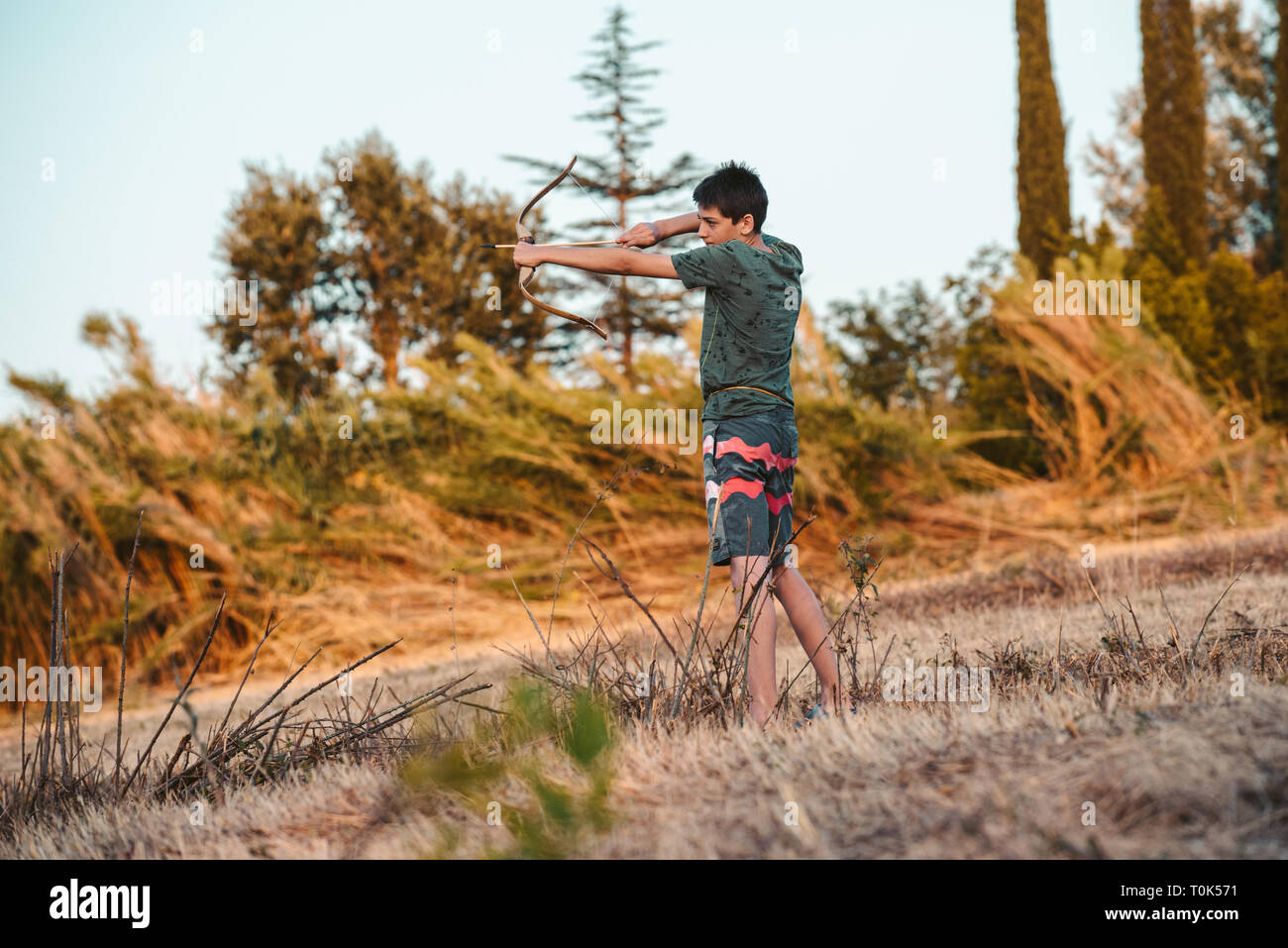 Young boy playing with bow and arrow in the beautiful fields, dry ...