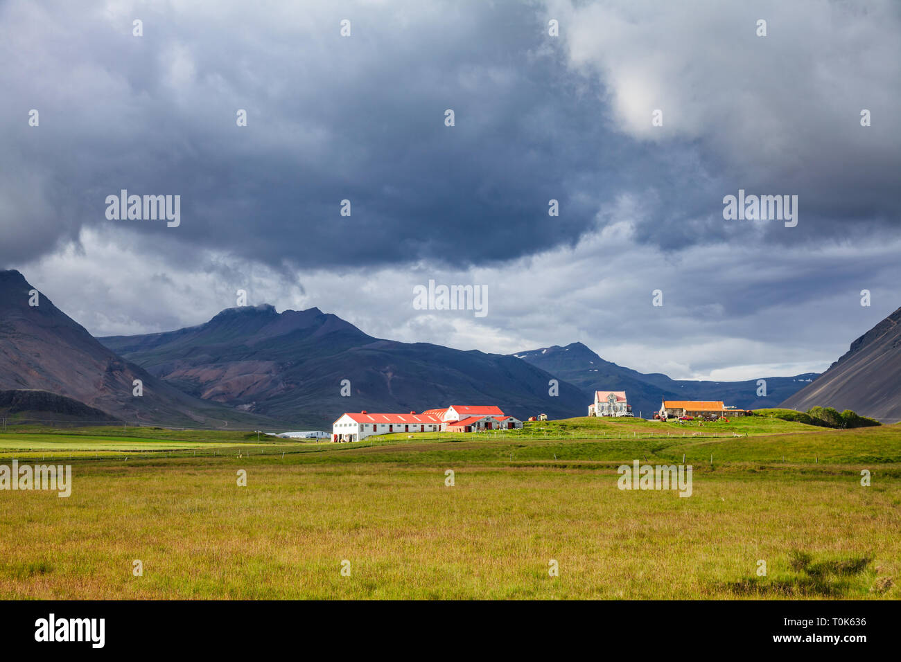 Icelandic rural landscape with farm houses under gloomy sky at the foot ...
