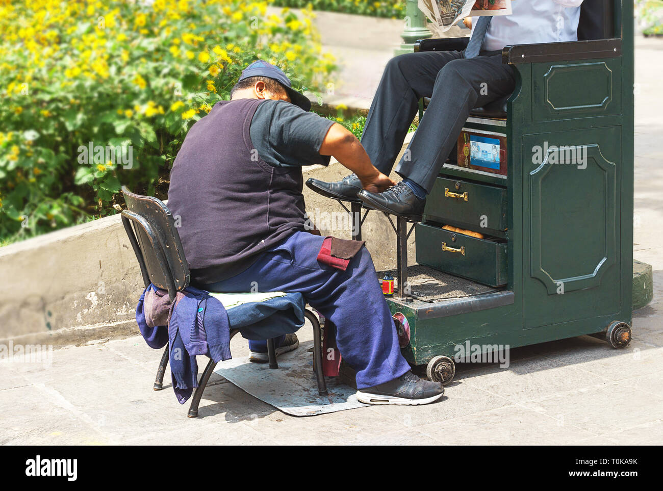 Shoe cleaner on the street brush and polish the shoes of businessman ...