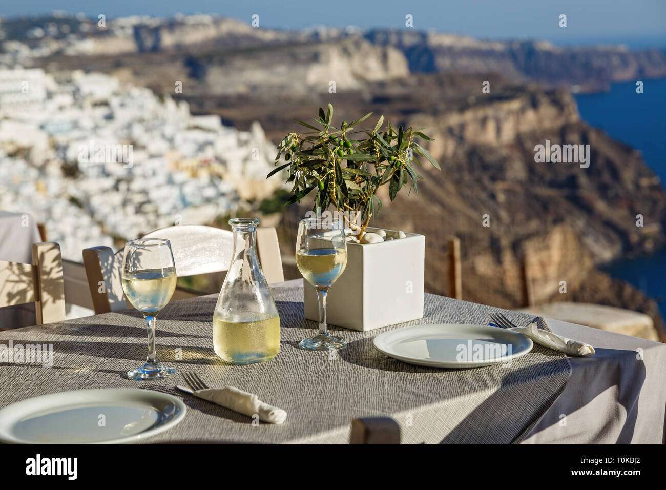 Table with a bottle of wine and glasses on the background of Santorini ...