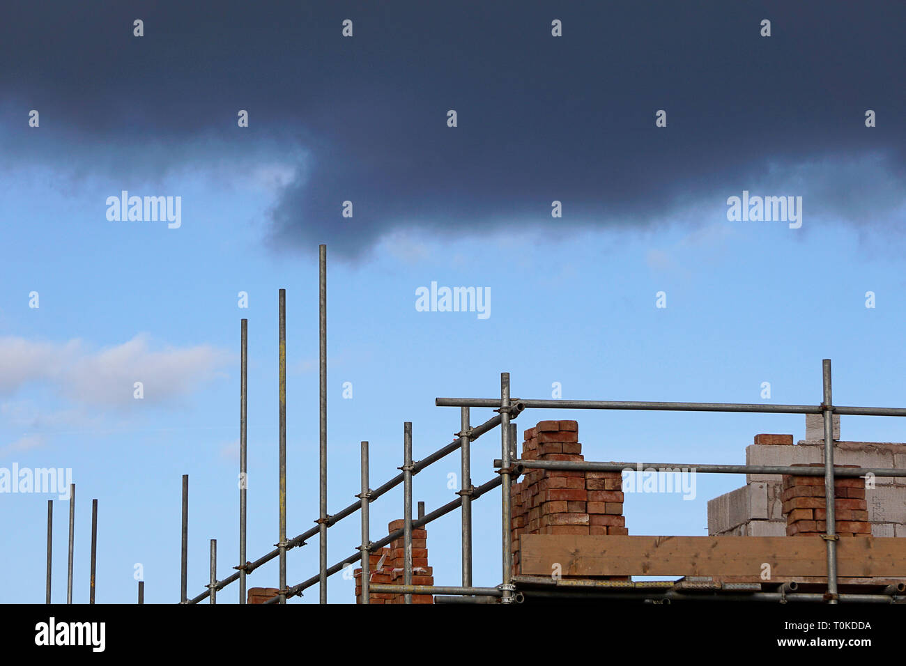 Storm clouds gathering over a building site with scaffolding and bricks ...