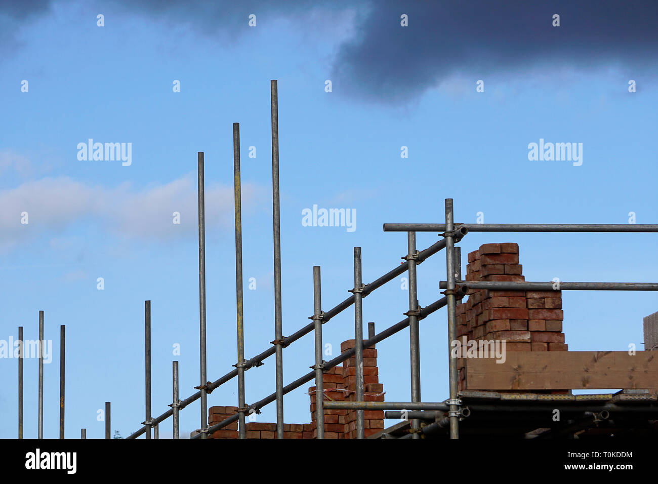 Storm clouds gathering over a building site with scaffolding and bricks ...