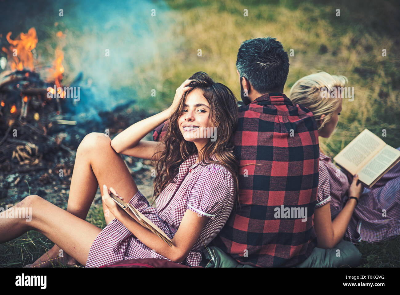 Camping in wilderness. Turn back guy looking at fire while two ...