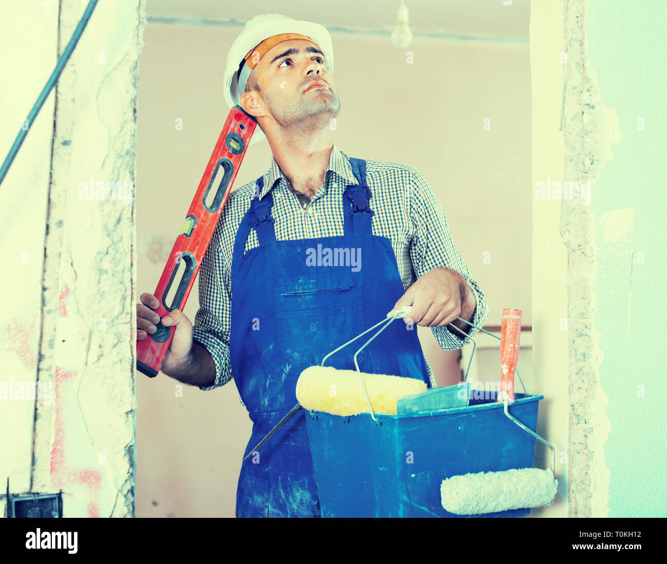 Portrait of constructor man which is standing with spirit level and ...