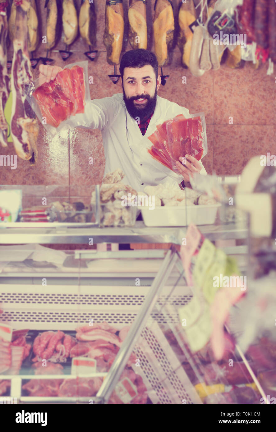 Smiling male seller showing sliced prosciutto in butcher’s store Stock ... Smiling male seller showing sliced prosciutto in butcher’s store Stock ...
