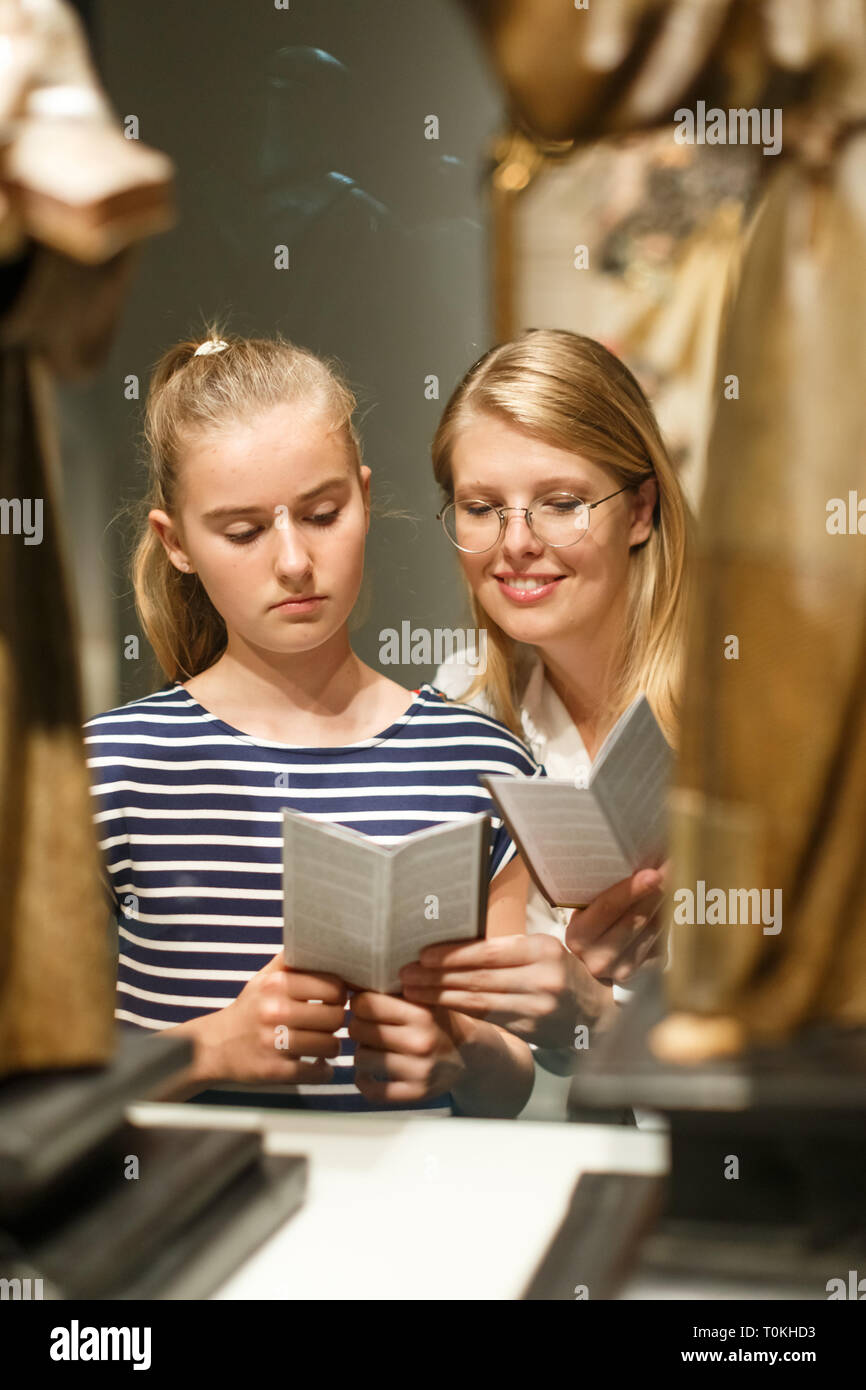 Portrait of woman visitor with daughter with guide book looking at ...
