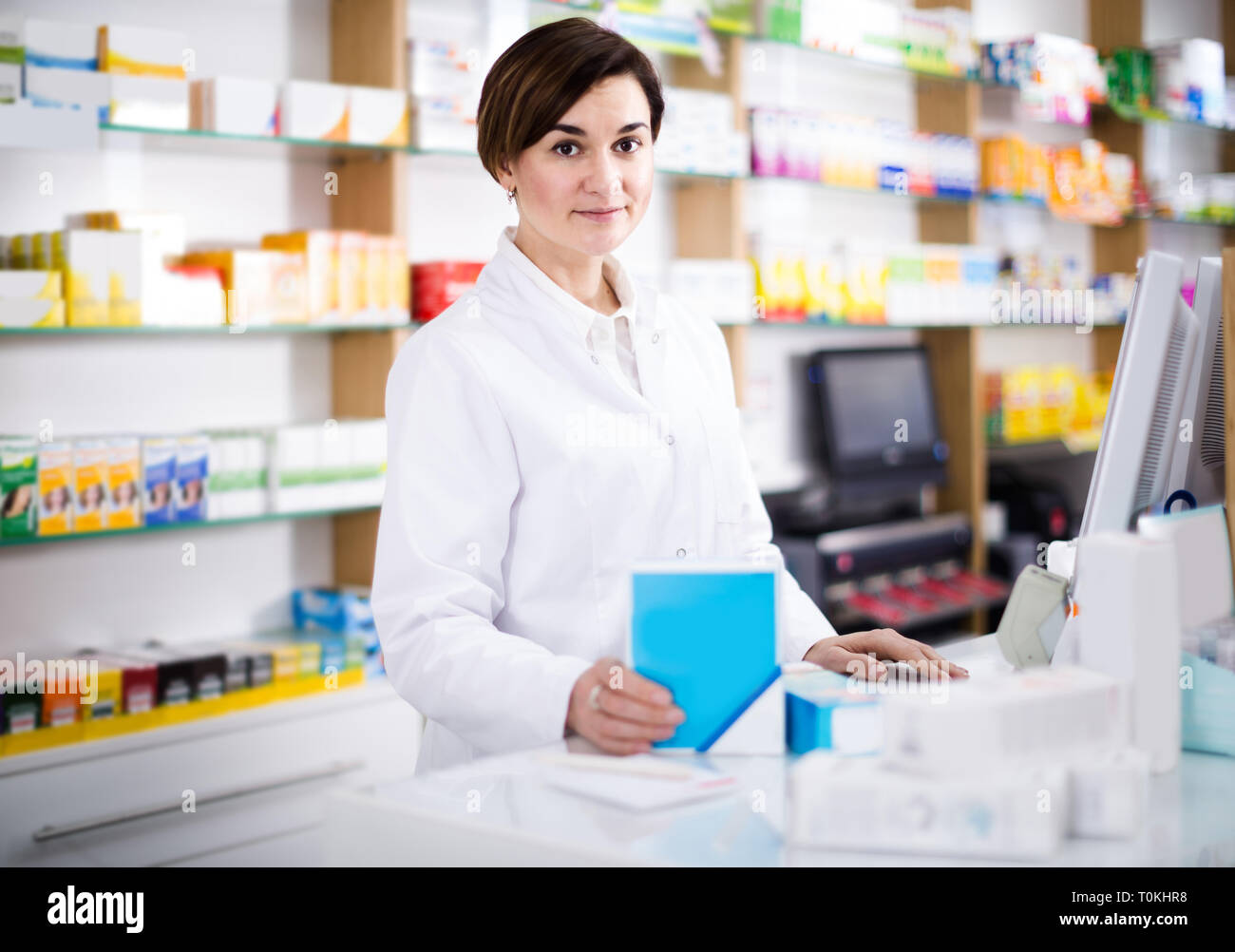 happy spanish female pharmacist offering assistance at counter in ...