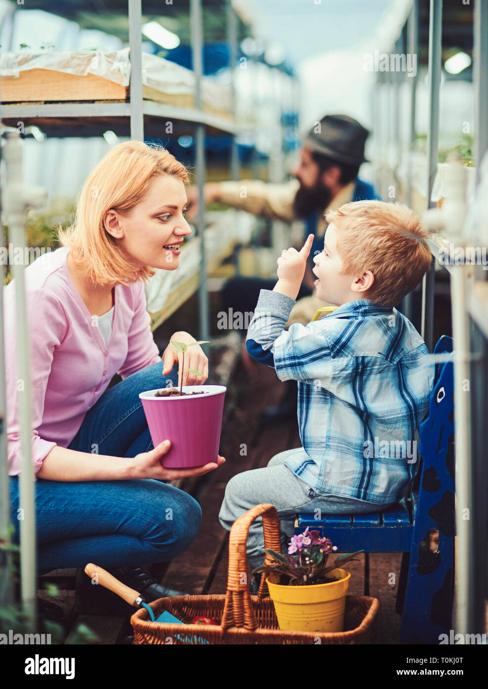 Blond kid talking to his mum while pointing up. Mother and son sitting ...