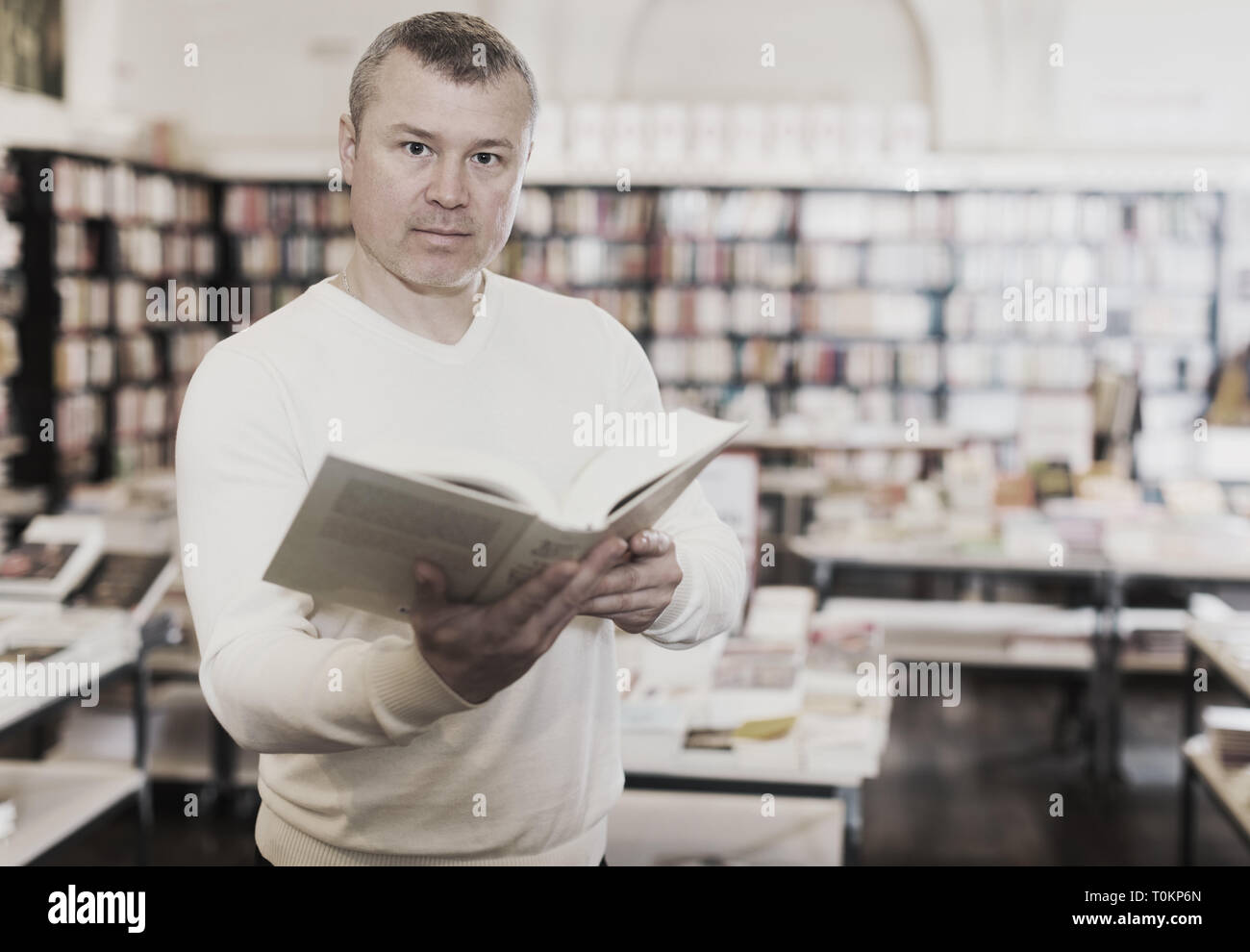 Intelligent man reading interesting books in bookstore Stock Photo - Alamy