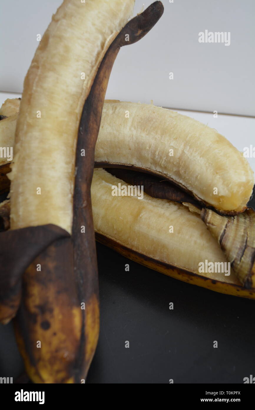 3 over ripe bananas on black plate Stock Photo - Alamy