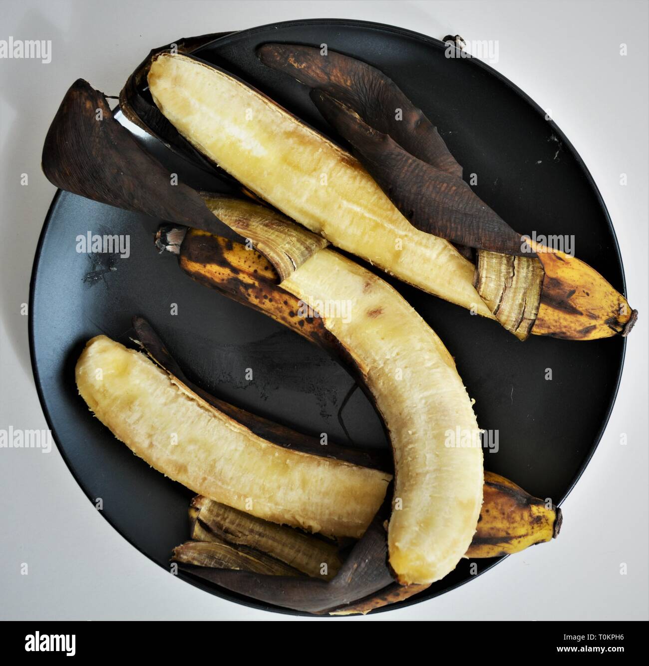 3 over ripe bananas on black plate Stock Photo - Alamy