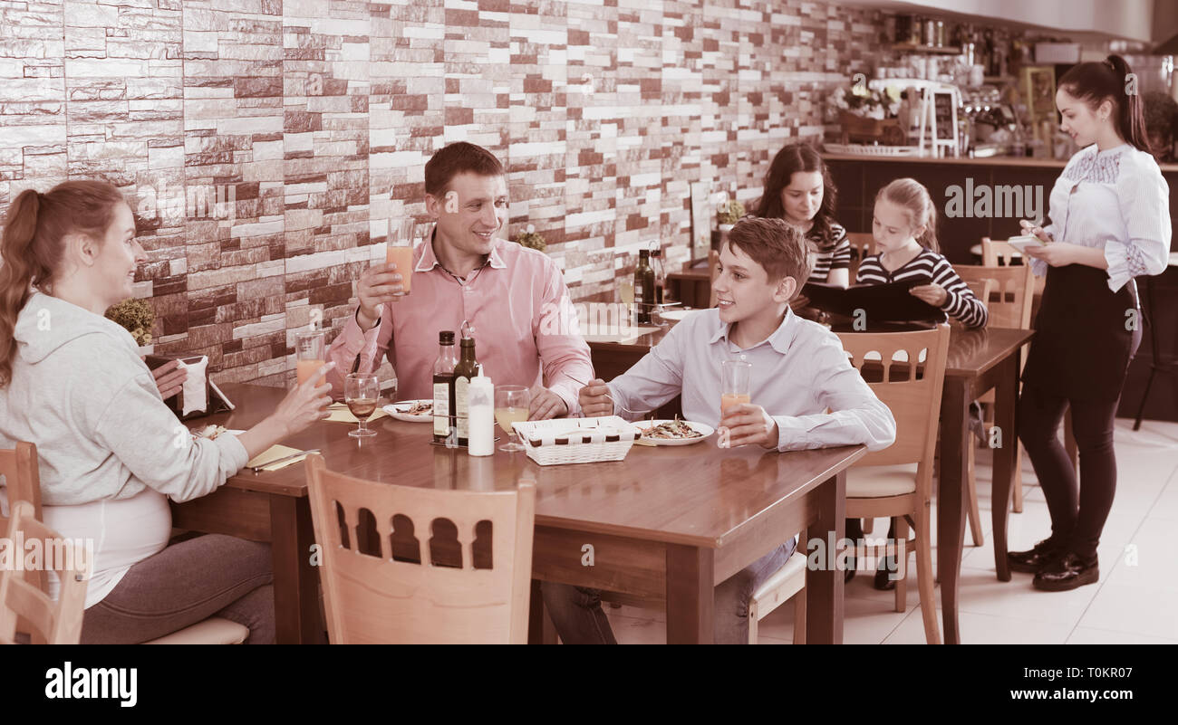 Cheerful family having conversation at dining table in cafe Stock Photo ...