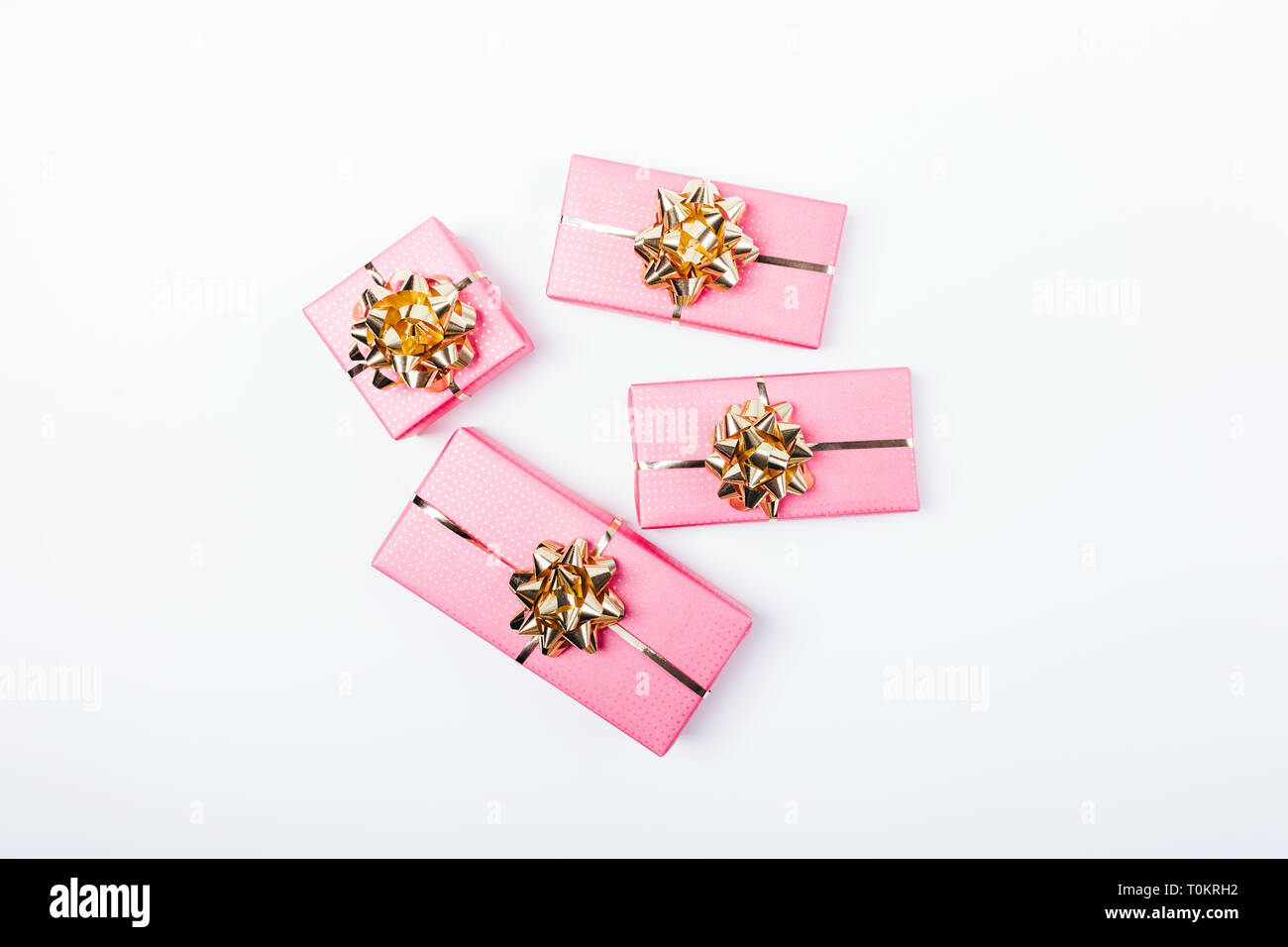 Flat lay composition of bright pink packaged gifts with golden bows on ...