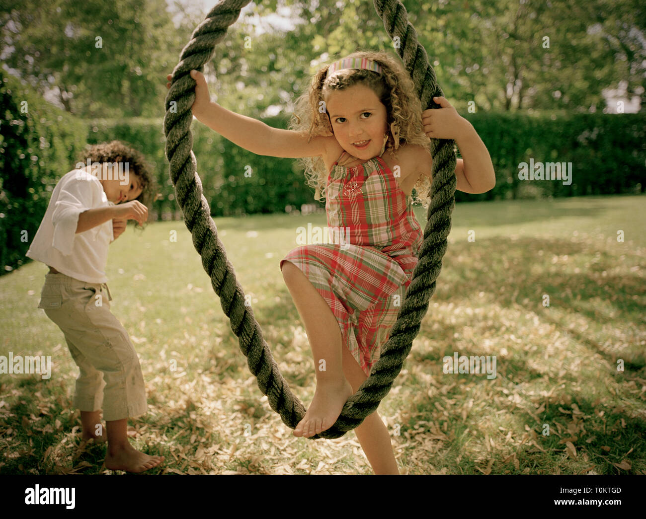 Two girls playing on a swing Stock Photo - Alamy