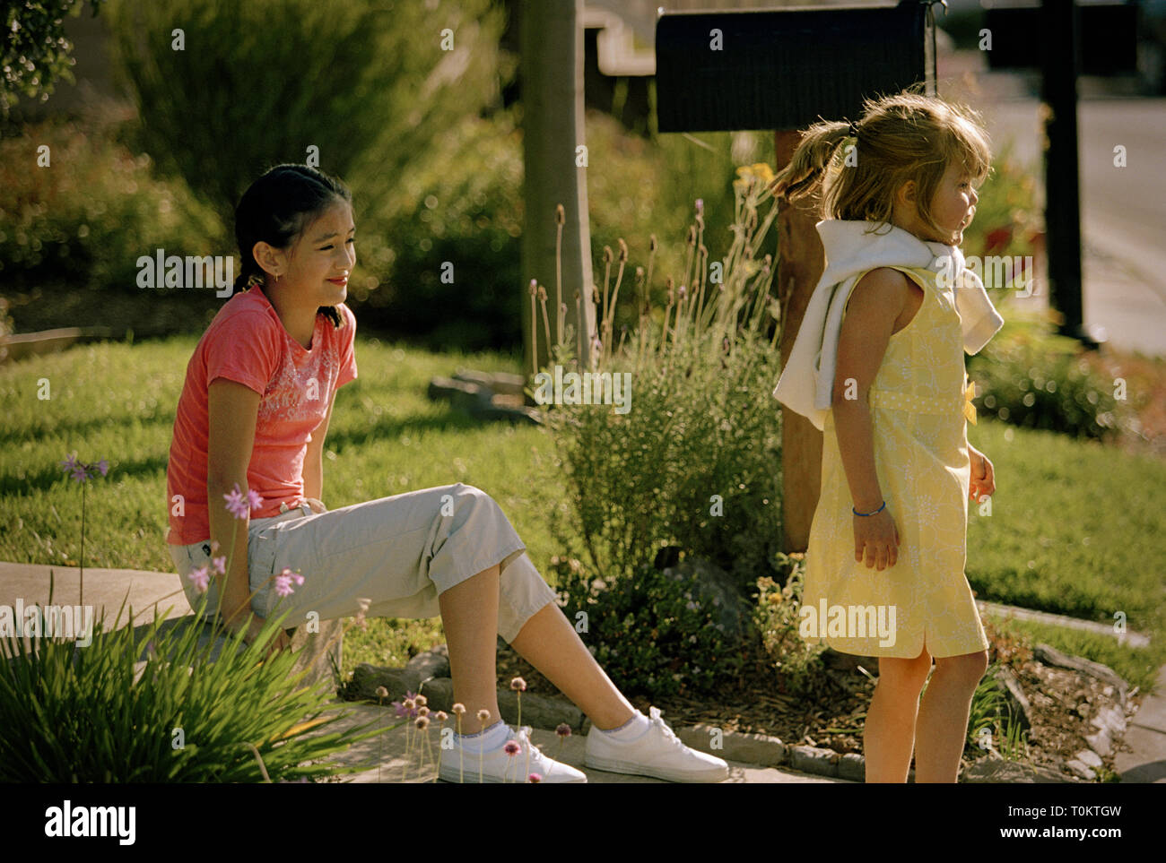 Teenage girl and her sister waiting outside their house Stock Photo - Alamy
