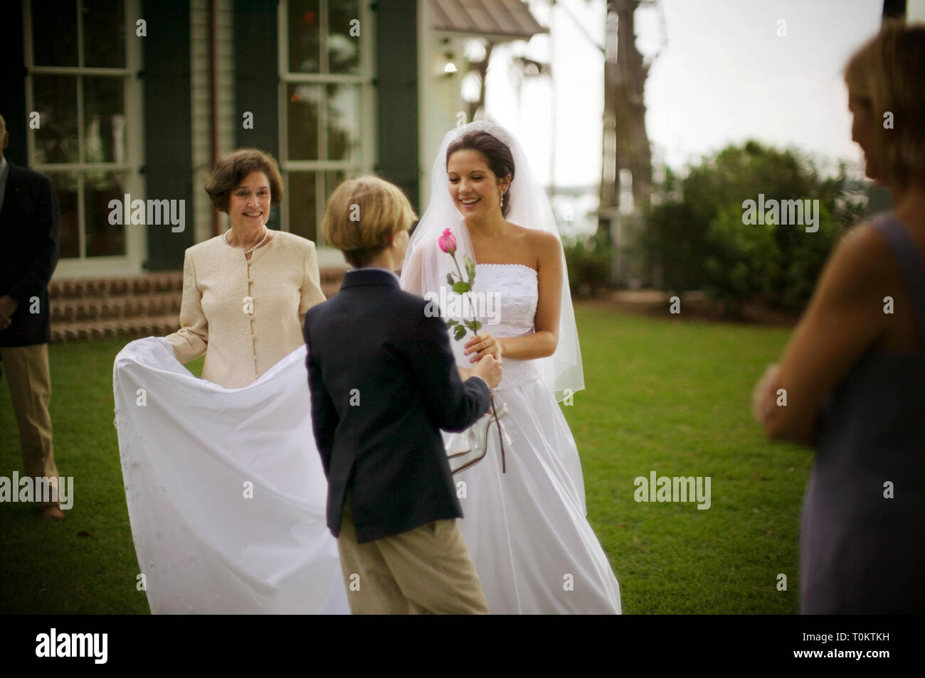 Boy giving a rose to a young adult bride as family look on Stock Photo ...