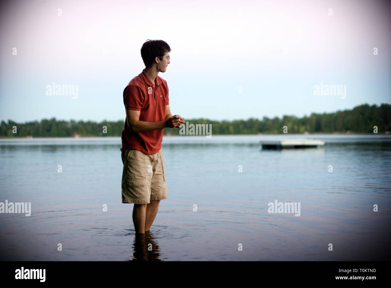 Side view of a teenage boy throwing stone in the river Stock Photo - Alamy