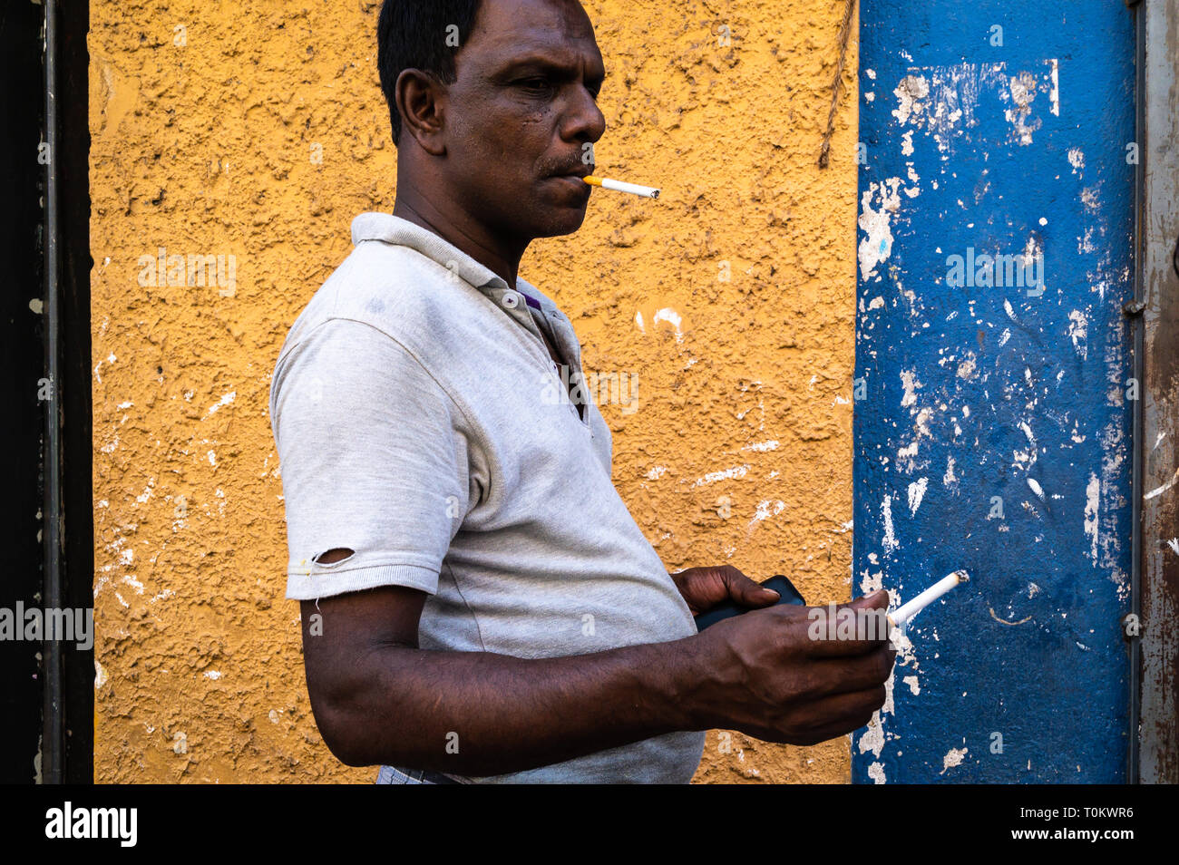 Man smoking a cigarette while holding another, Colombo, Sri Lanka Stock ...
