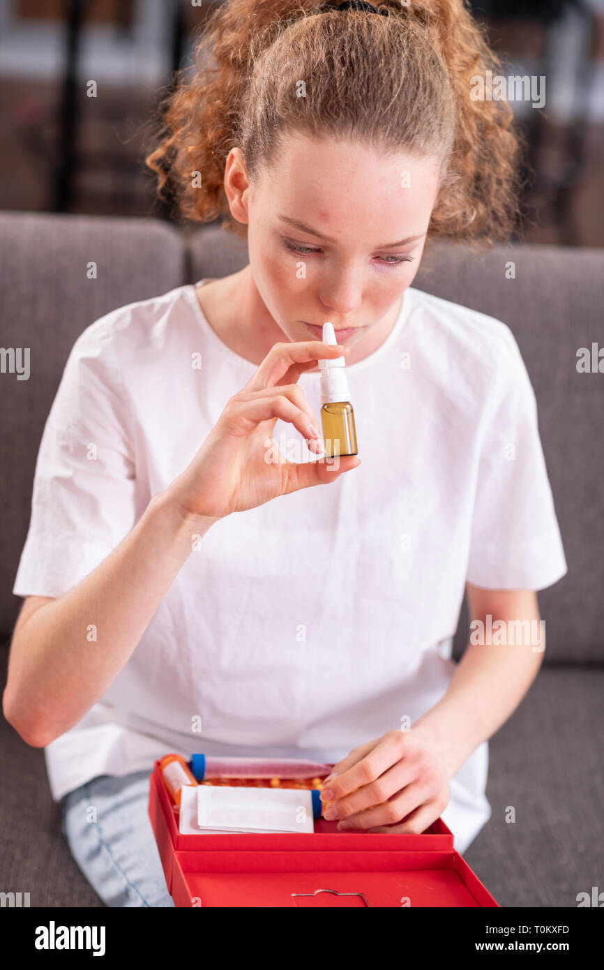 Worried Long Haired Girl Inserting Spray Bottle Into Her Nose Stock
