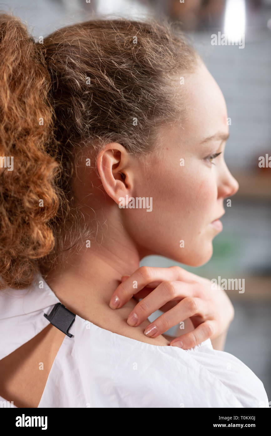 Annoyed curly-haired good-looking woman scratching her back Stock Photo ...