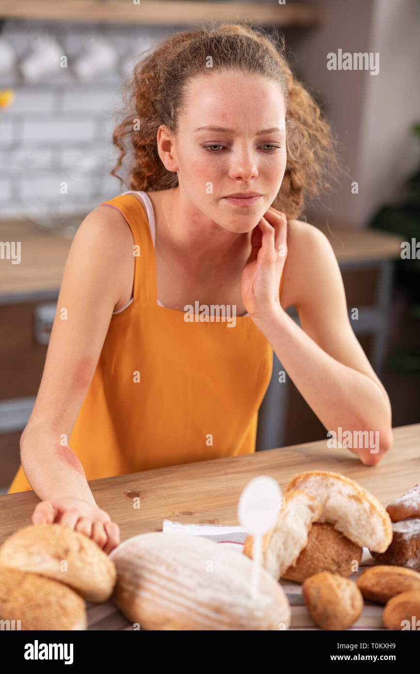 Unpleasant Good Looking Young Lady Leaning On Kitchen Table And Rubbing