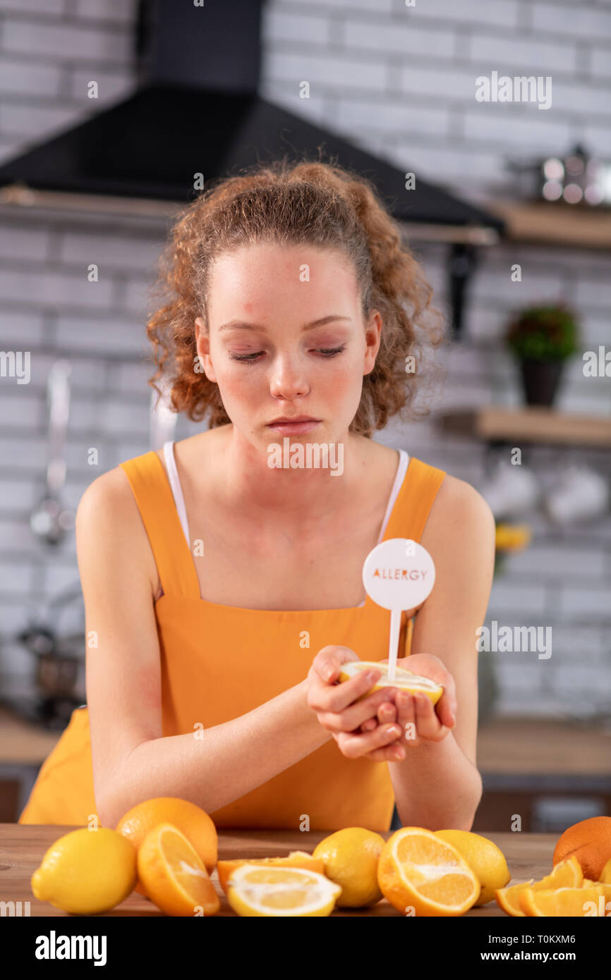 Resolute angry girl staying near kitchen table covered with lemons and ...