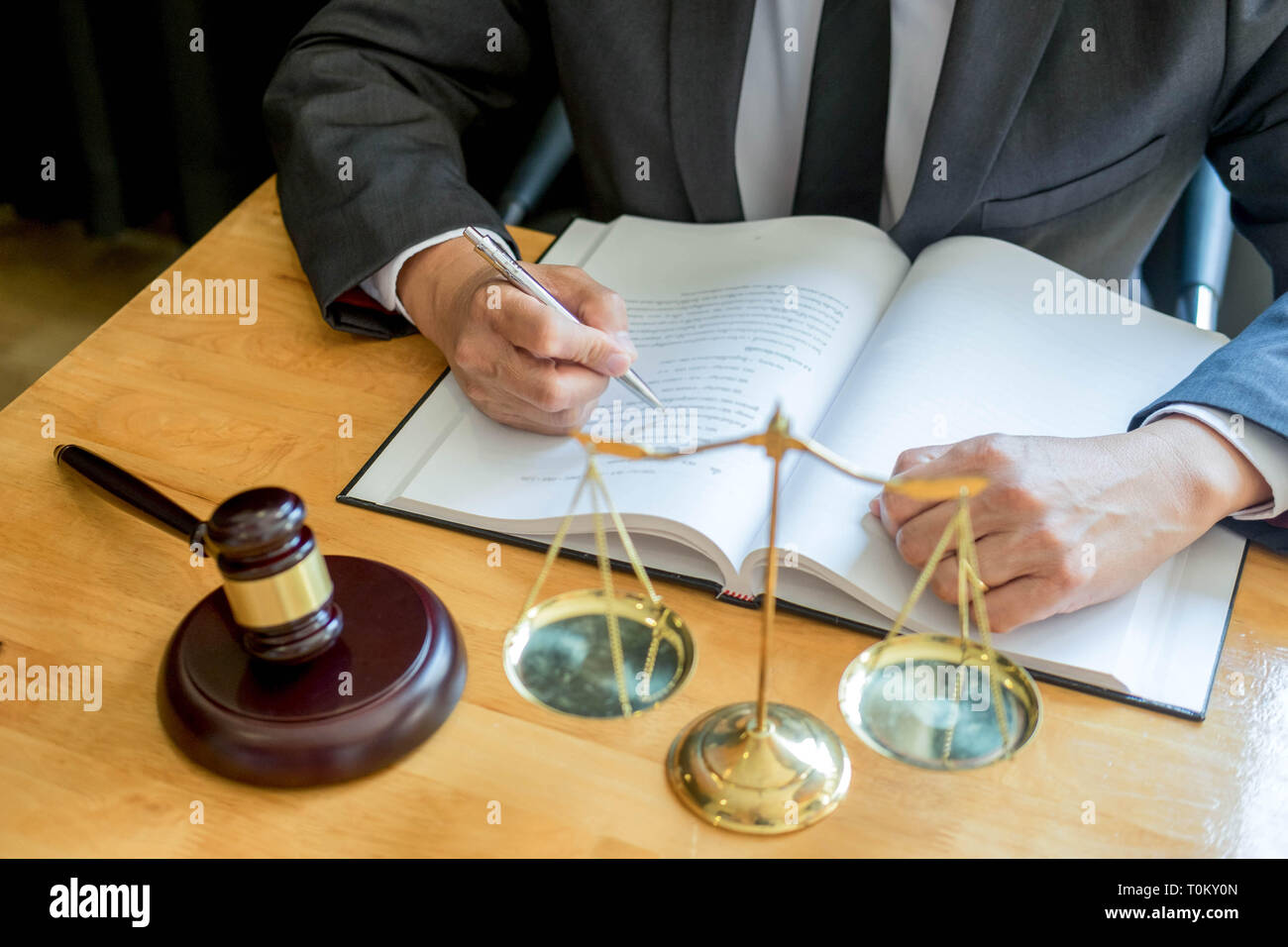 Male lawyer working with contract papers and reading law book in a ...