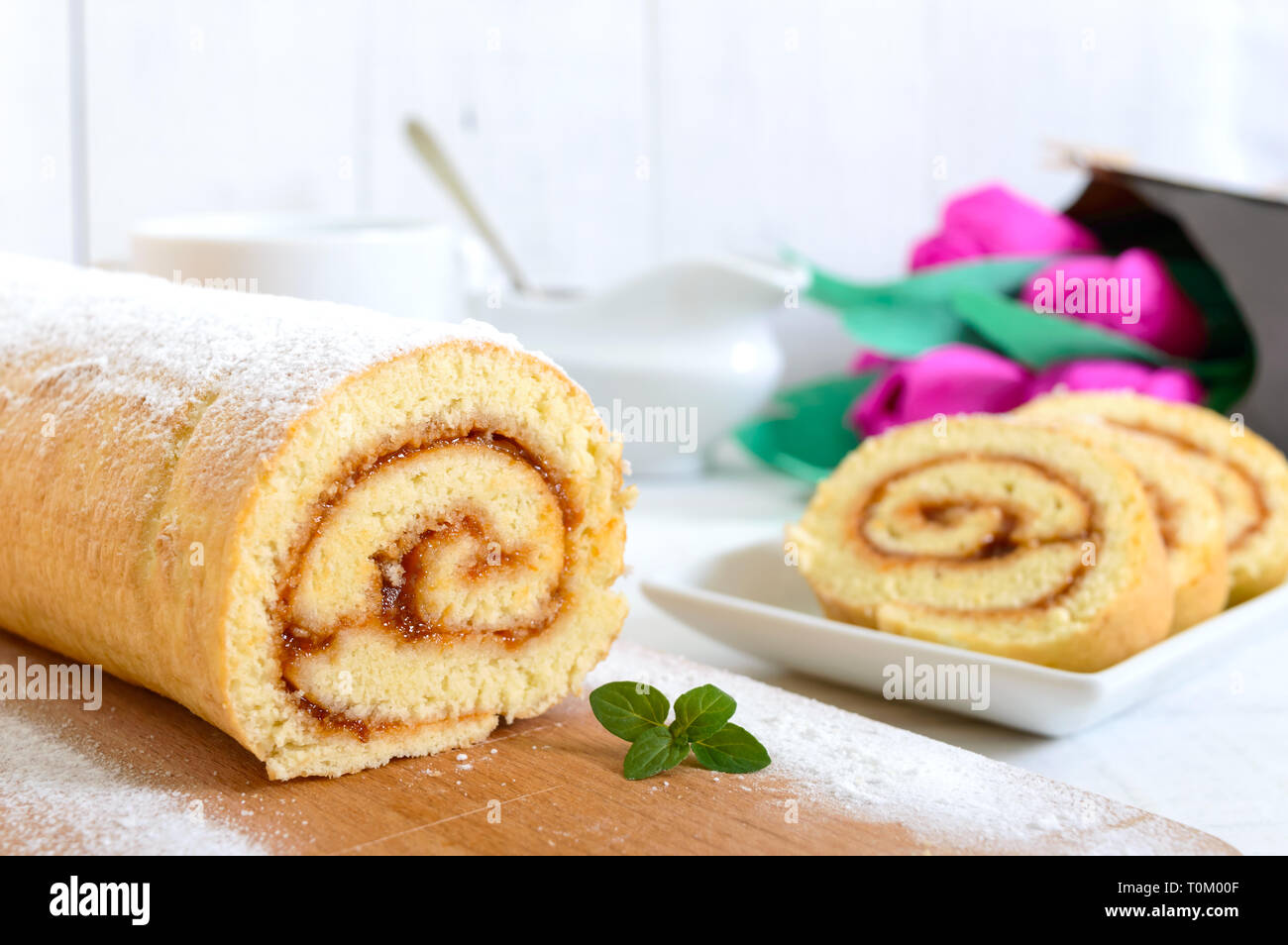 Delicious biscuit roll with apricot jam on a white wooden table ...