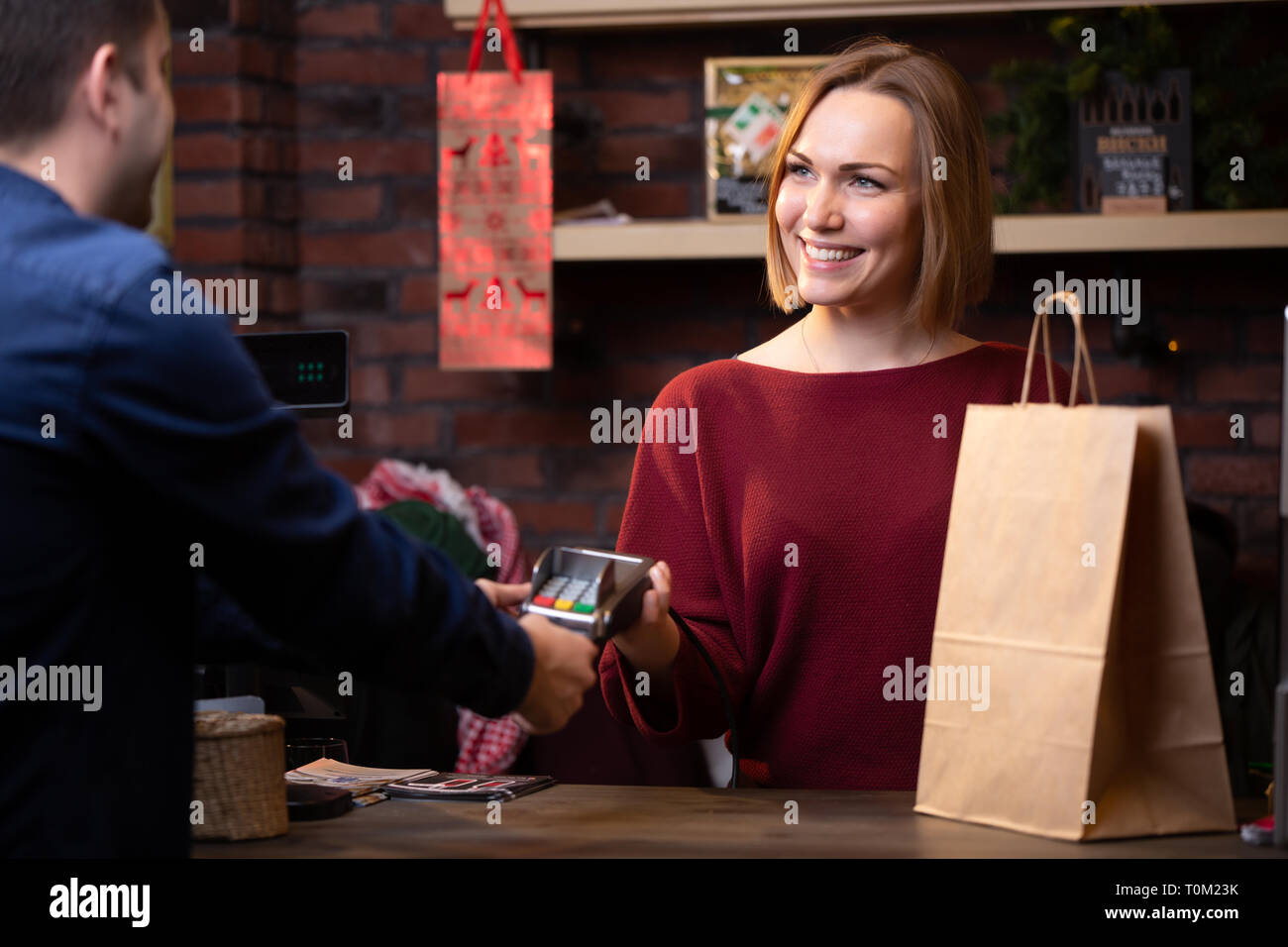 Picture of smiling seller woman standing behind cash register and male ...