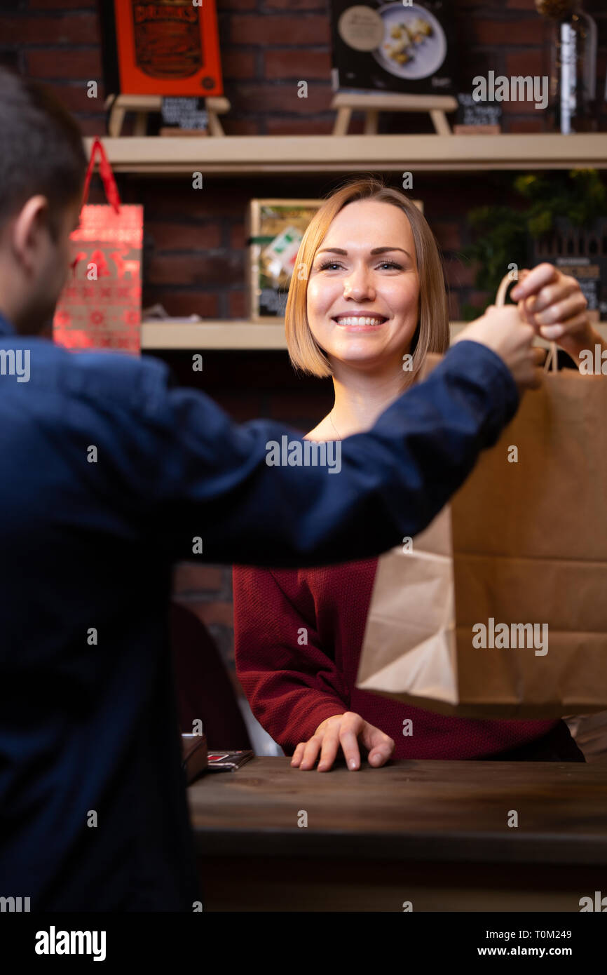 Picture of smiling seller blonde giving paper bag to man Stock Photo ... Picture of smiling seller blonde giving paper bag to man Stock Photo ...