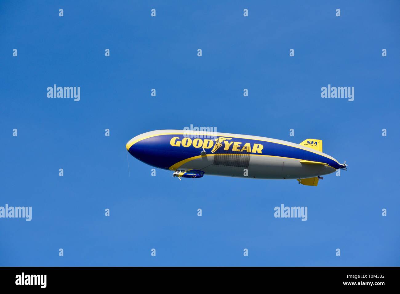 Famous Goodyear blimp dirigible soaring overhead in flight in bright ...