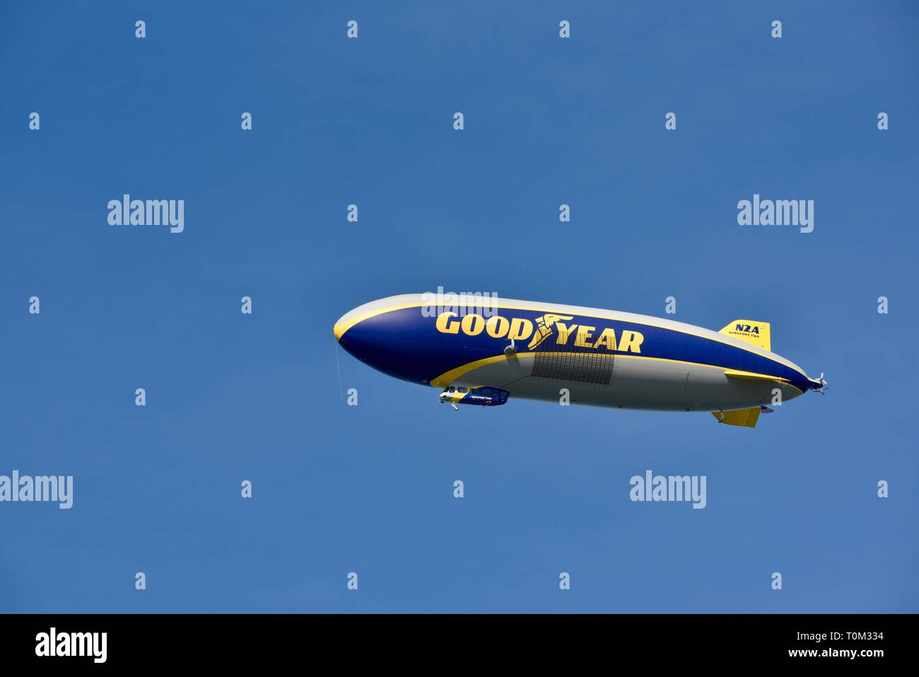 Famous Goodyear blimp dirigible soaring overhead in flight in bright ...