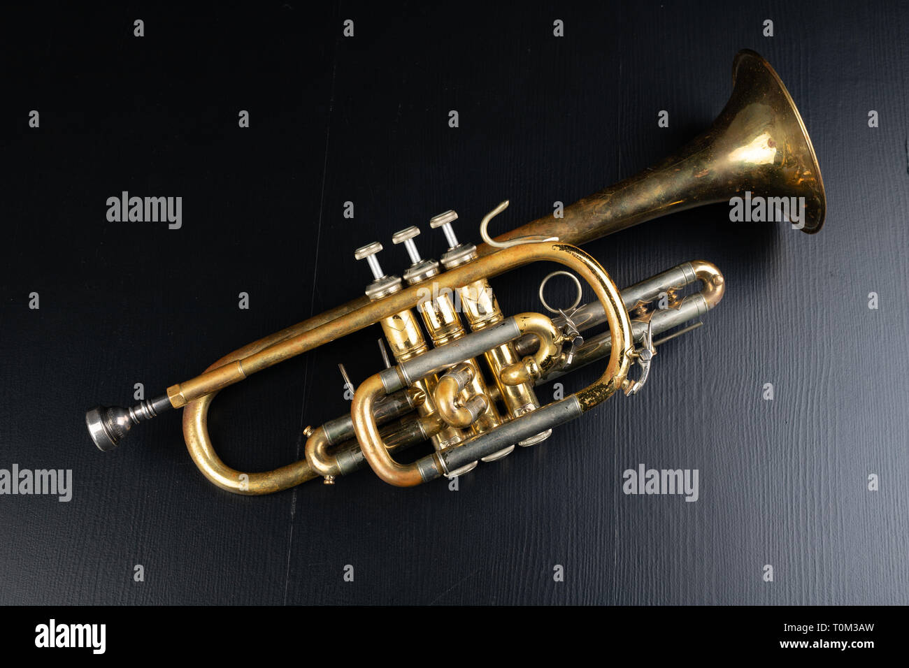 Old coated patina trumpet on a dark table. An inedible musical ...
