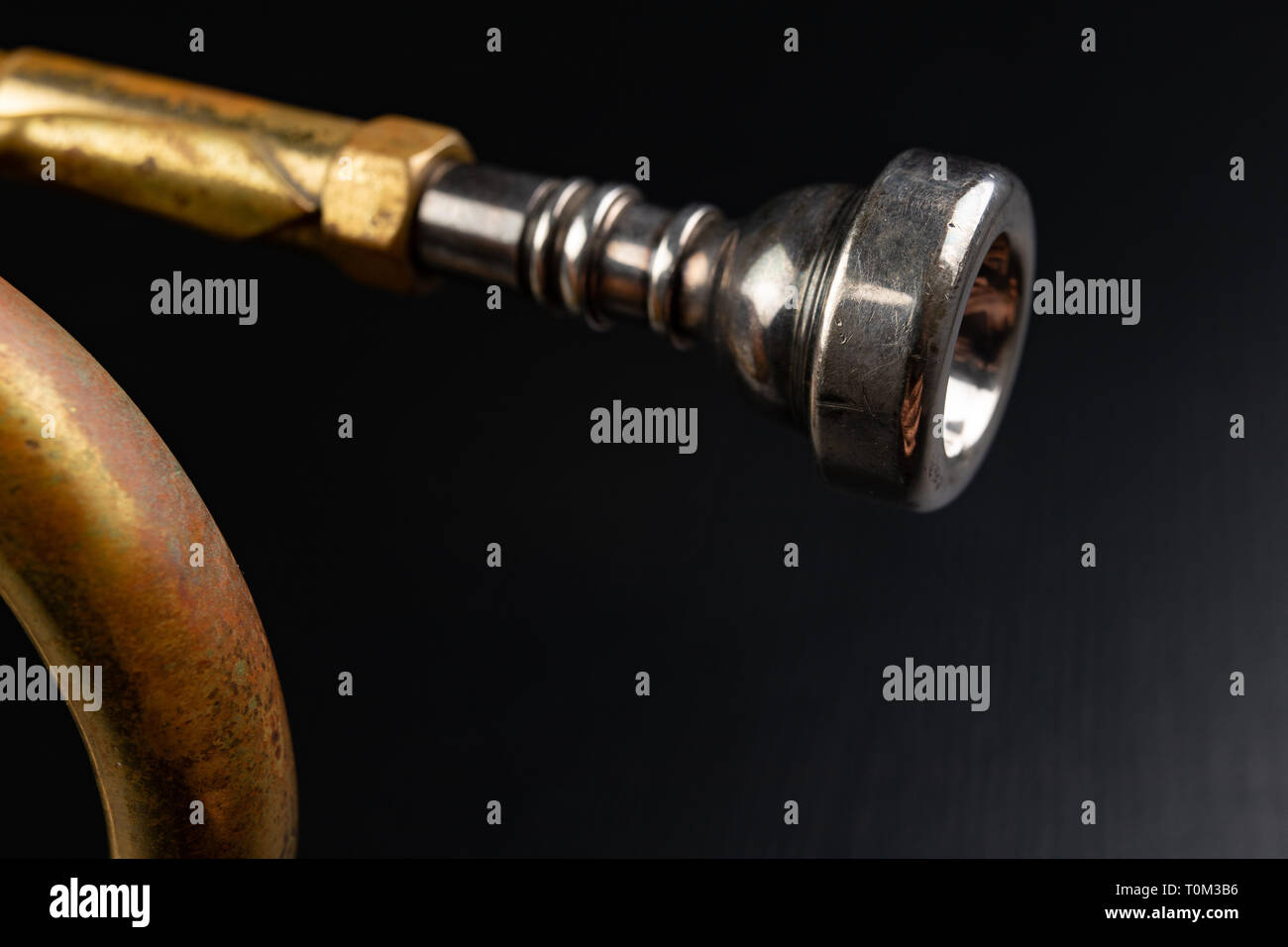 Old coated patina trumpet on a dark table. An inedible musical ...